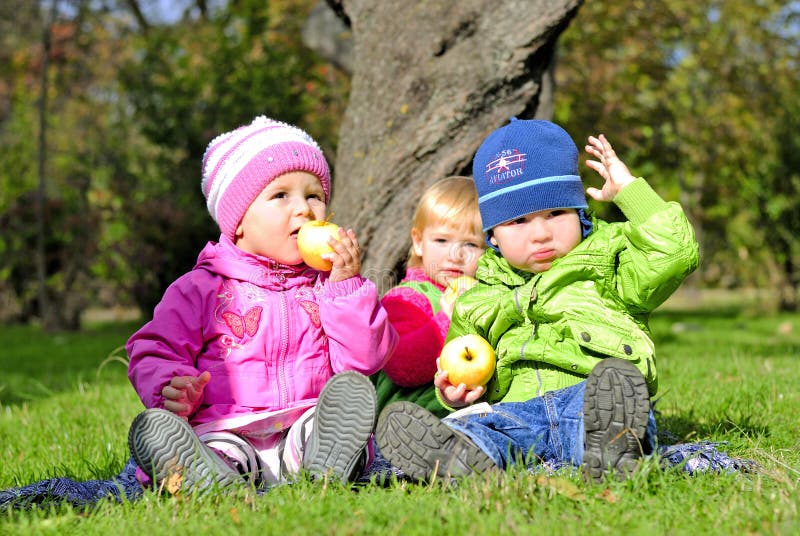 Three Small Children Sit on a Green Clearing Stock Photo - Image of ...