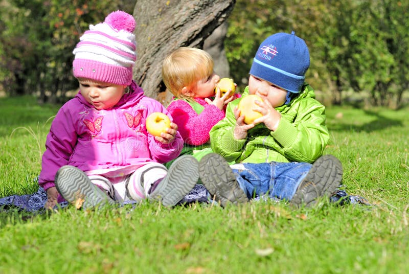 Three Small Children Sit on a Green Clearing Stock Photo - Image of ...