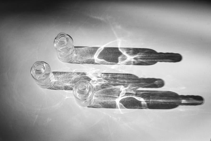 Three Small Glass Bottles Cast a Shadow on a White Table Stock Image ...