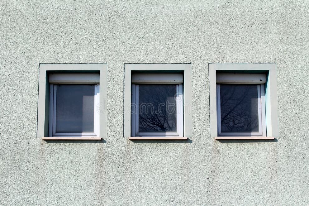 Three Small Windows in a Row with Tree Branches in Reflection and White ...