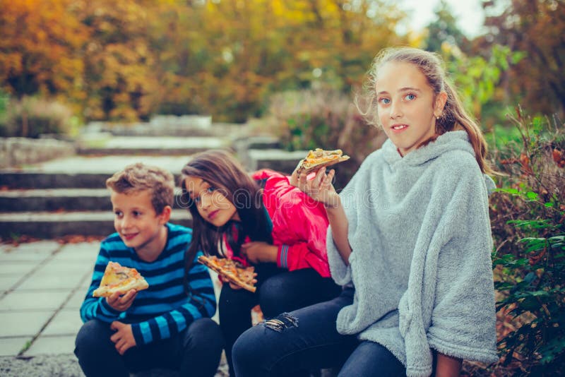 Three Smiling Children, Talking and Eating Pizza Outdoors Stock Image ...