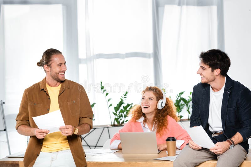 Three Smiling Friends Doing Paperwork and Looking at Each Other Stock ...