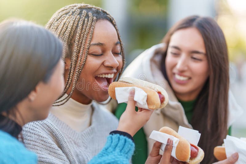 Three Smiling Friends Eating Hot Dog in a Park Stock Image - Image of ...