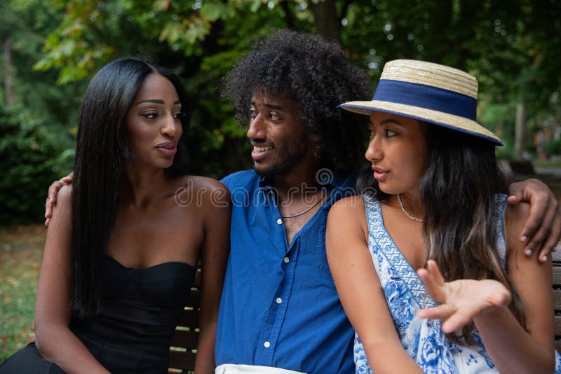 Three Smiling Multiracial Friends Sitting on the Park Bench Make Eye ...