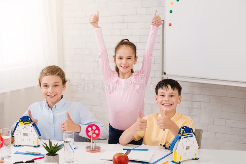 Three Smiling Students Giving Thumbs Up in a Classroom Setting Stock ...