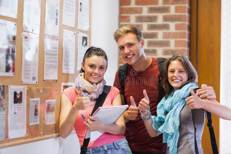 Three Smiling Students Standing Next To Notice Board Showing Thumbs Up ...