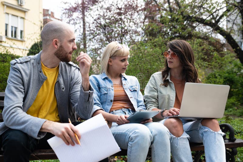 Three Students on a Bench in the Park Study Talking Typing on Laptop ...