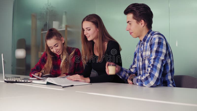 Three Students Working on Their Homework Sitting Together at the Table ...
