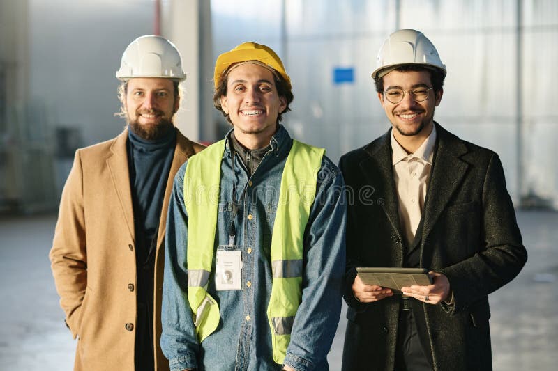 Three Successful Engineers in Protective Helmets Standing in Front of ...