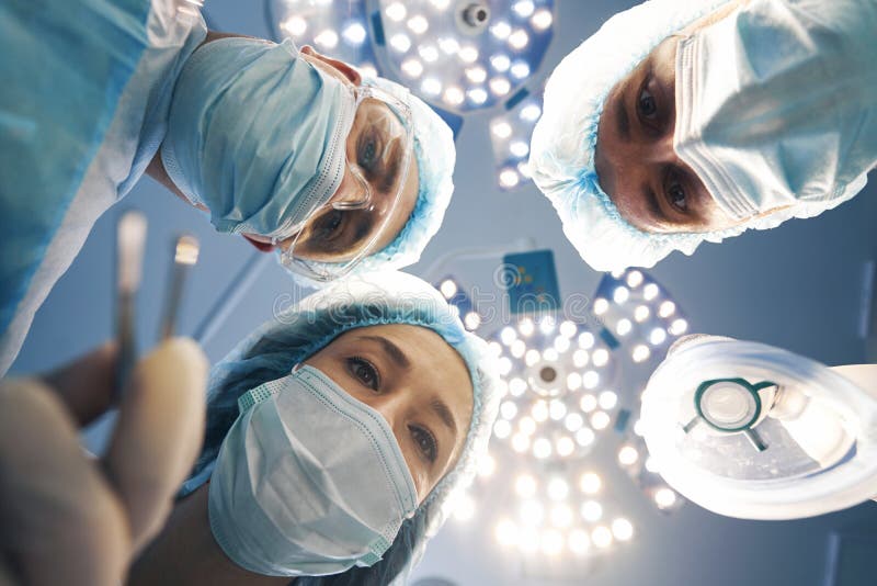 Three Surgeons Leaning Over Patient on Operating Table Stock Photo ...