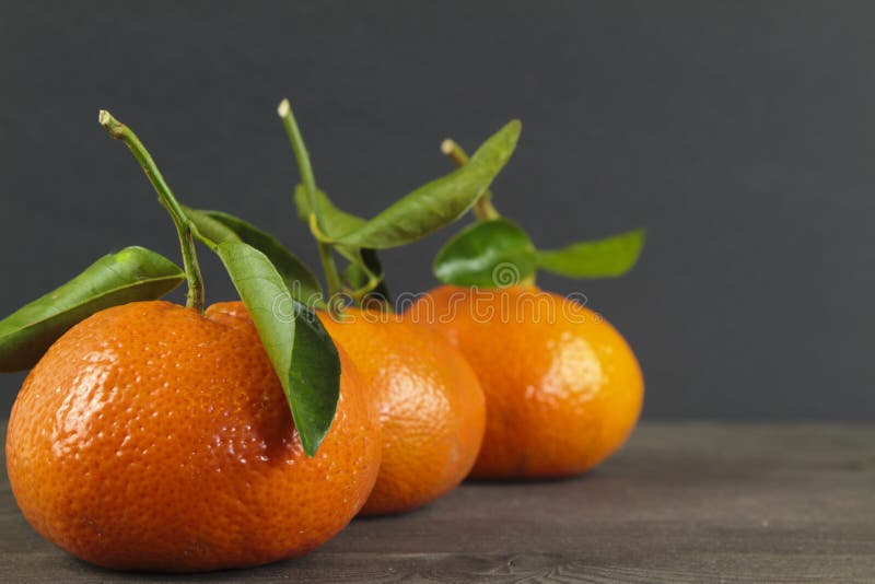 Three Tangerines with Green Leaves on Black Background Stock Photo ...