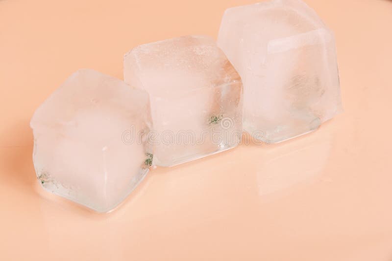 Three Translucent Ice Cubes Rest on a Peach-colored Surface Stock Photo ...