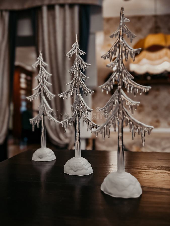 Three Transparent Figures of Christmas Trees Stand on a Dark Shelf ...