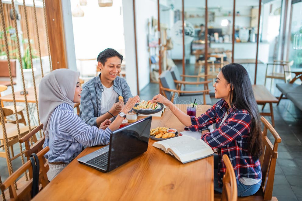 Three University Students Chat Over a Snack while Doing Group Work ...
