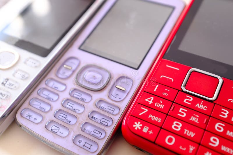 Three Vintage Colorful Cell Phone Display on White Table Stock Image ...