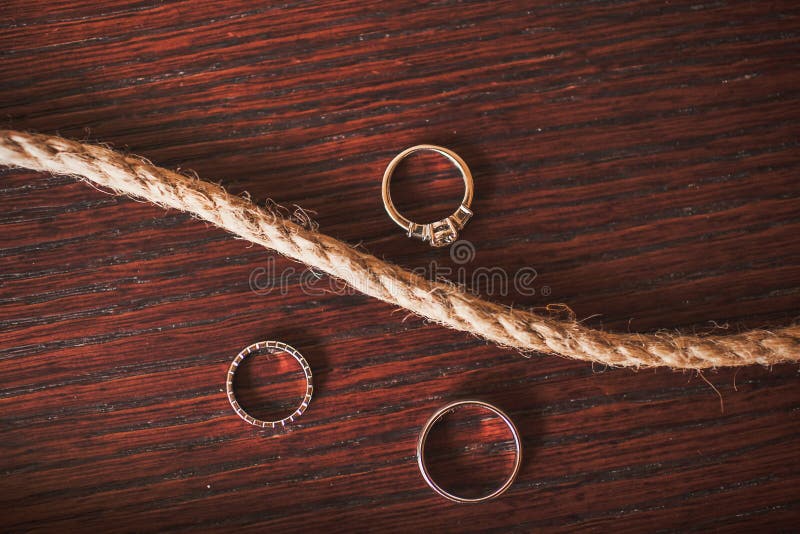 Three Wedding Rings on a Wooden Table between a Rope Stock Photo ...