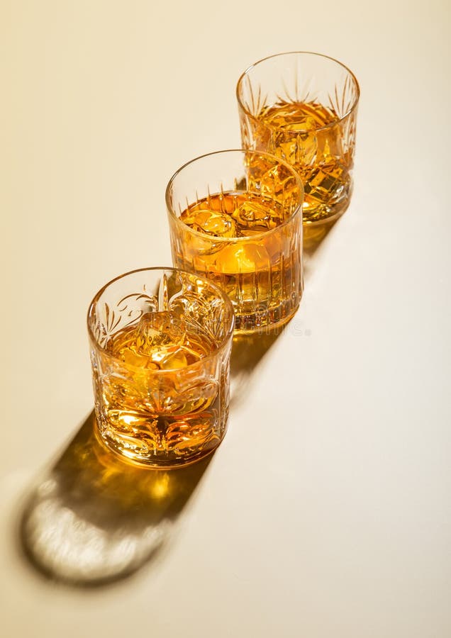 Three Whiskey Glasses with Ice Cubes on Golden Background Stock Photo ... Three Whiskey Glasses with Ice Cubes on Golden Background Stock Photo ...
