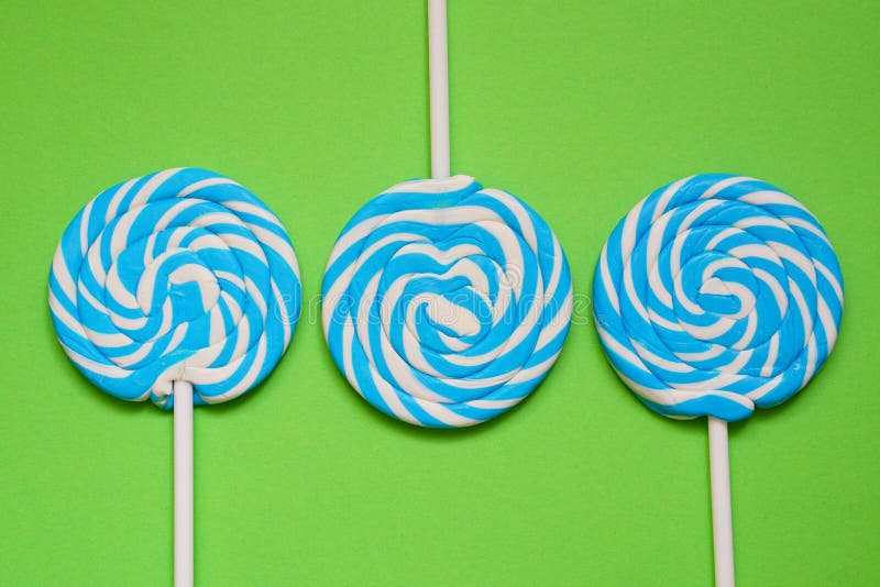 Three White and Blue Lollipops on Green Background Stock Image - Image ...