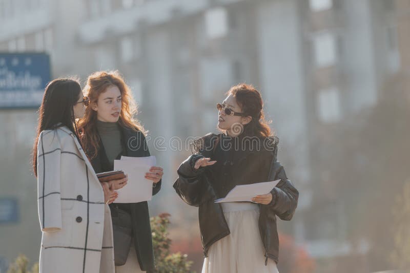 Three Women Discussing Documents Outdoors during a Sunny Day Stock ...