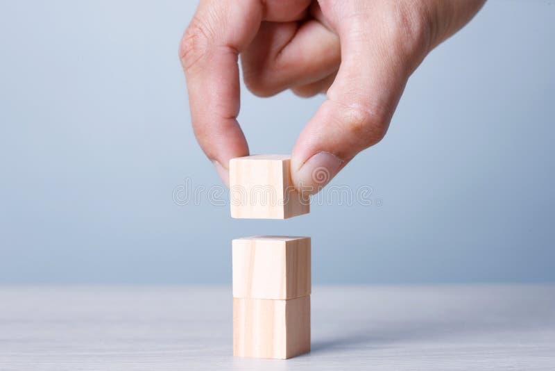 Three Wood Block Cubic Stack with Hand on Table Blue Tone Background ...