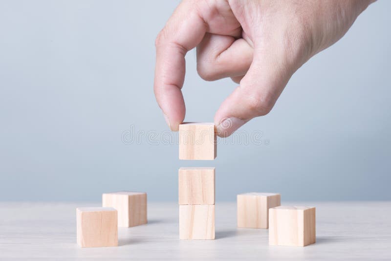 Three Wood Block Cubic Stack with Hand on Table Blue Tone Background ...