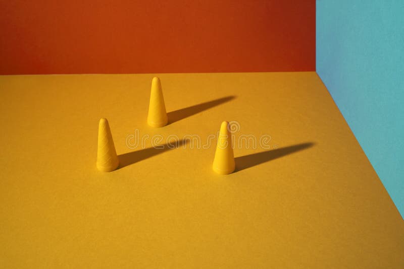 Three Yellow Cones with Distance and Hard Shadow on a Flat Colored ...