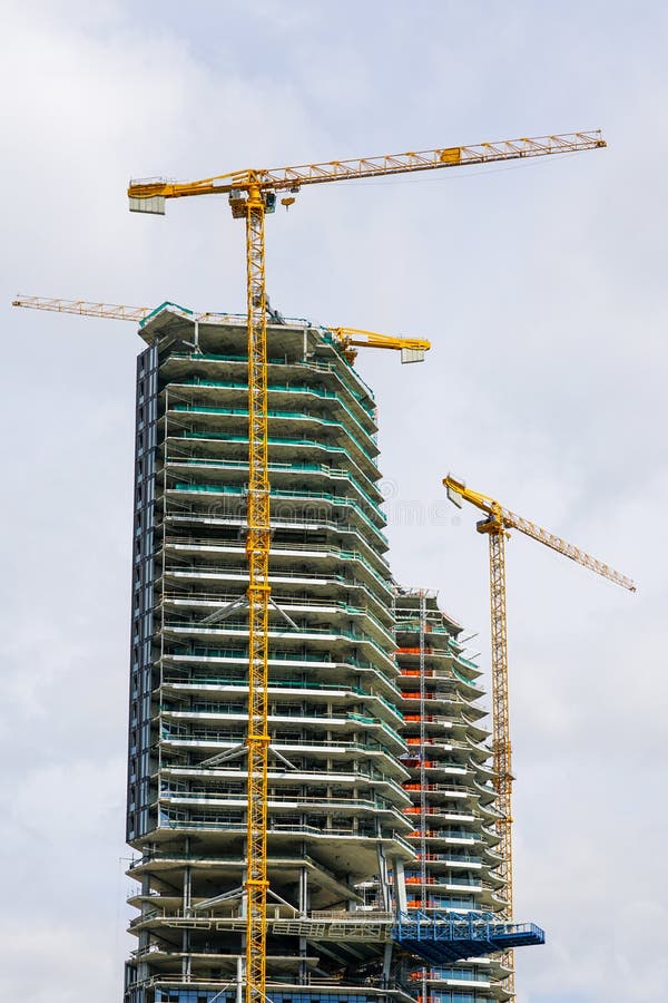 Three Yellow Tower Cranes and a Fragment of the Facade of an Unfinished ...