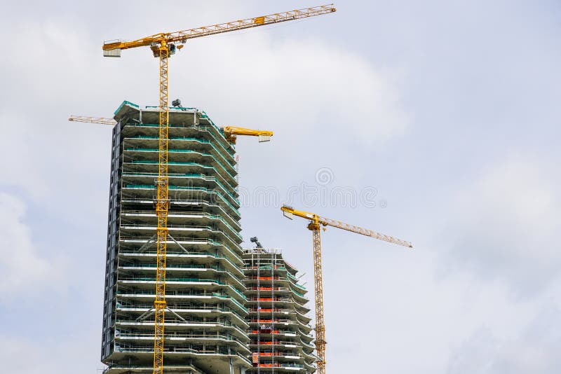 Three Yellow Tower Cranes and a Fragment of the Facade of an Unfinished ...