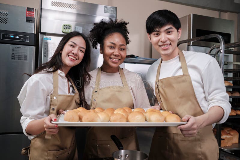 Three Young Chefs with Baking Bread, Smile and are Cheerful in the ...