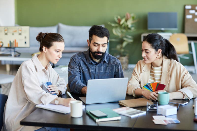 Three Young Creative Designers Watching Online Training about Trendy ...