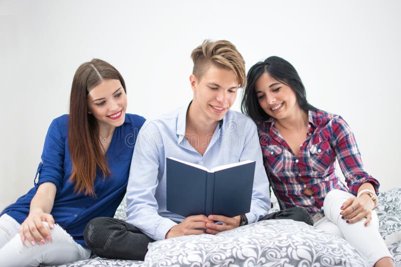 Three Young Friends Reading Book Together while Sitting on Coach at ...