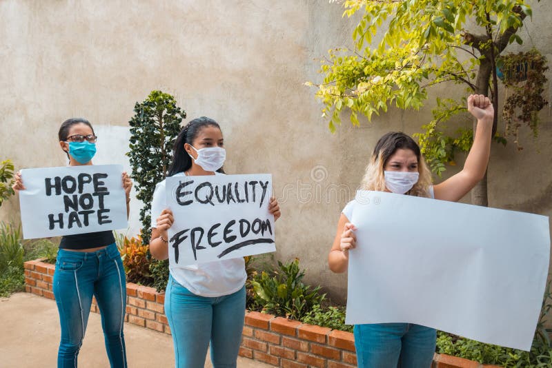 Three Young Hispanic Women at a Protest Holding Posters with Free Copy ...