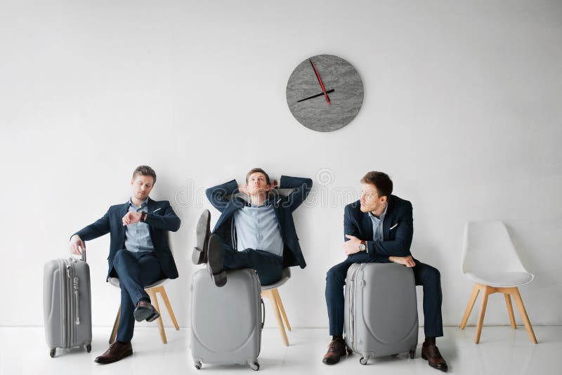 Three Young Men Sit on White Chairs and Wait for Flight. they Look ...