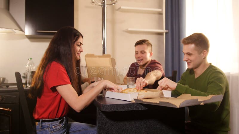Three Young People Sitting in Kitchen and Eating Pizza Stock Image ...