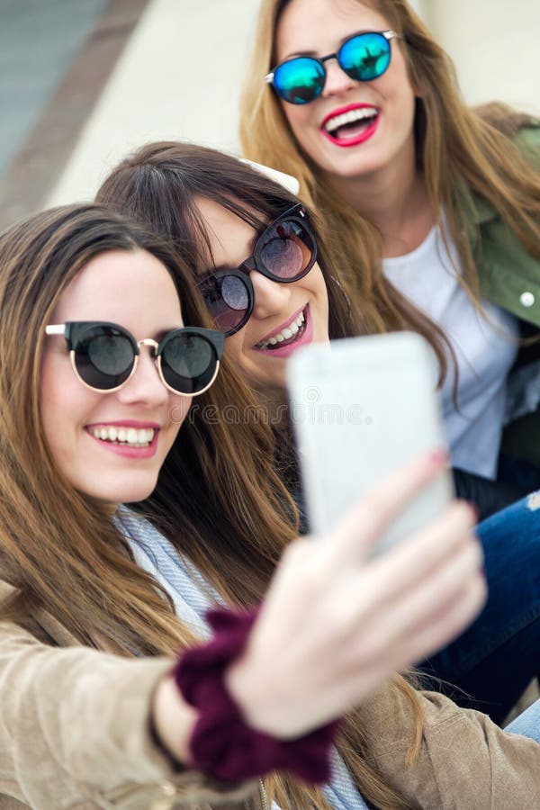 Three Young Women Using a Mobile Phone in the Street. Stock Image ...