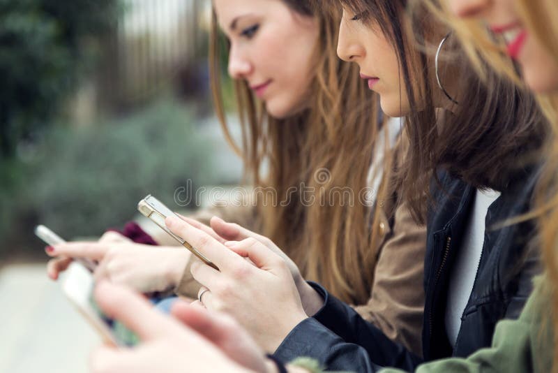 Three Young Women Using a Mobile Phone in the Street. Stock Image ...