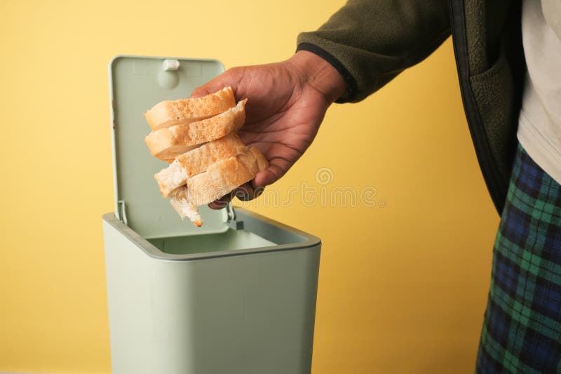 Throwing Bread Slices into a Trash Bin on Yellow Backdrop Stock Photo ...