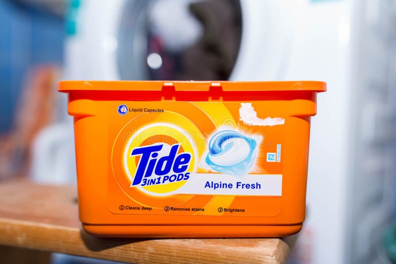 Tide Washing Liquid Capsules in Front of a Washing Machine. Editorial ...