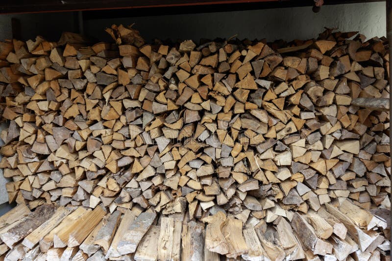 A Tightly Packed Stack of Split Firewood Logs Leaning Against a Dark ...