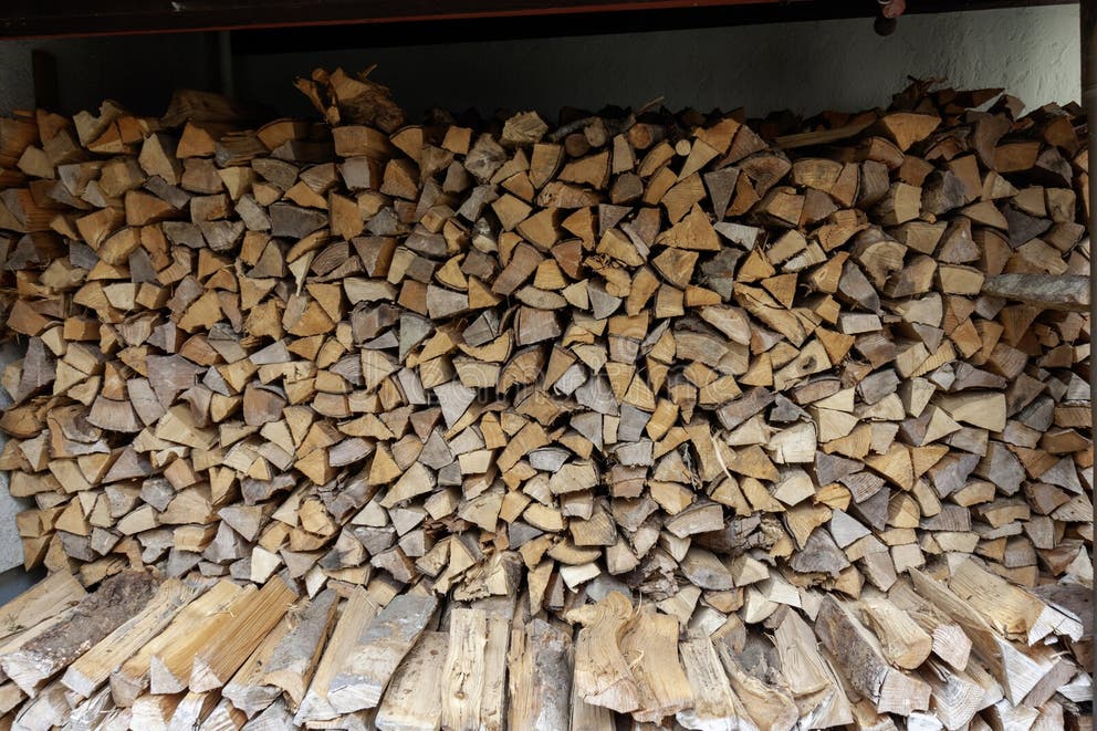 A Tightly Packed Stack of Split Firewood Logs Leaning Against a Dark ...