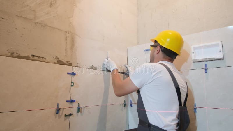 Tiler Installing Large Size Tile on Wall. the Tiler Performs the Work ...