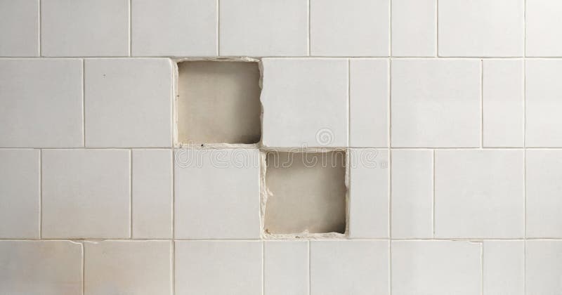 White Tiled Wall with Two Missing Tiles, Revealing the Underlying ...