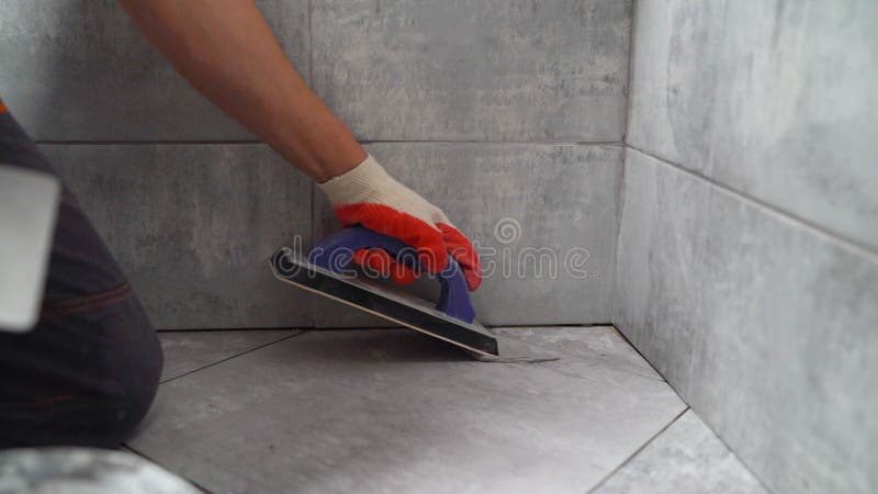 Construction Worker Applying Grout To Floor Tiles in Bathroom ...
