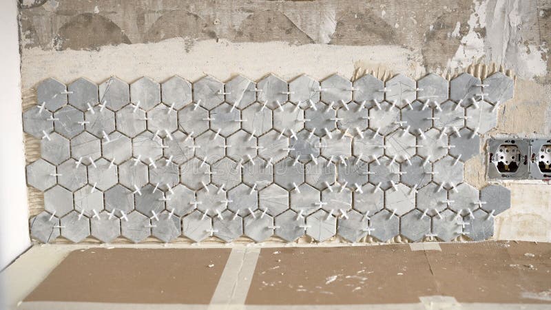 Tiler Installing Hexagonal Marble Tiles on Bathroom Wall Using Tile ...