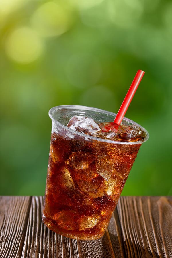 Tilted Plastic Glass of Cola with Ice on Wooden Table Outdoors Stock ...