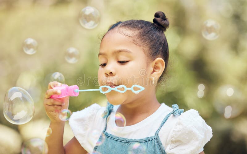 Tiny Bubbles. a Little Girl Blowing Bubbles in a Garden at Home. Stock ...