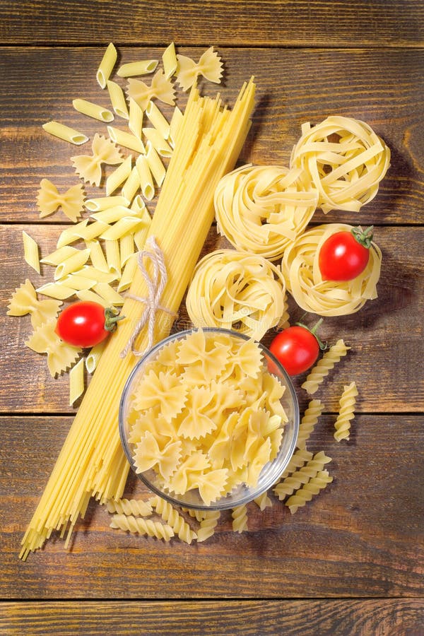 Tipos Da Massa Seca Com Tomates De Cereja Em Um Fundo De Madeira Marrom ...
