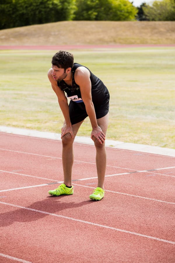 Tired Athlete Sitting on the Running Track and Drinking Water Stock ...