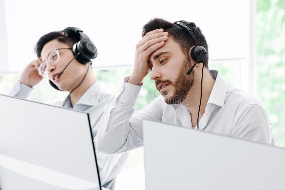Tired Call Centre Operator and His Colleagues Communicating with ...