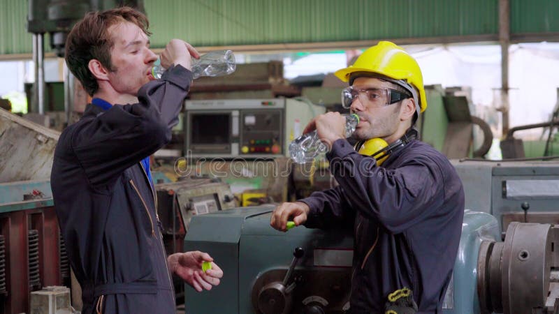 Tired Factory Workers Taking a Break and Talking To Coworker in the ...